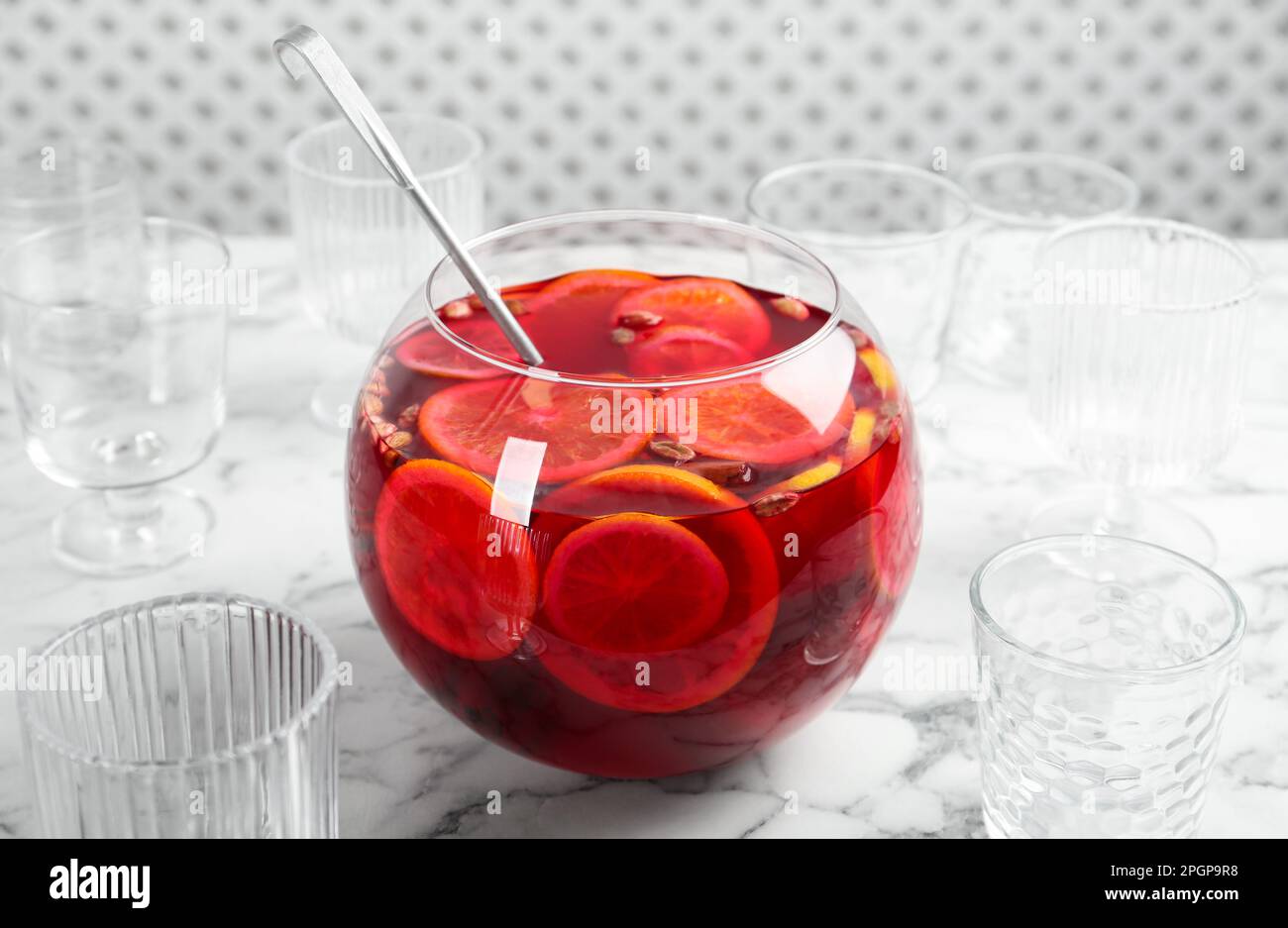 Bowl of delicious aromatic punch drink, ladle and empty glasses on ...