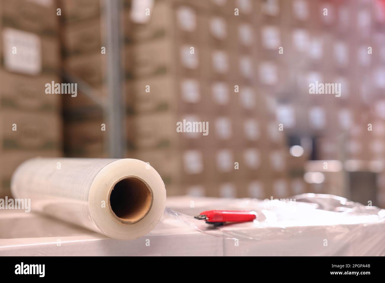 Roll of stretch film and utility knife on wrapped boxes in warehouse ...