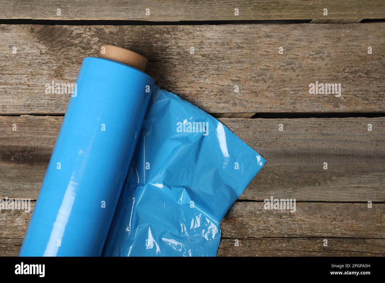 Roll of plastic stretch wrap film on wooden table, top view. Space for ...
