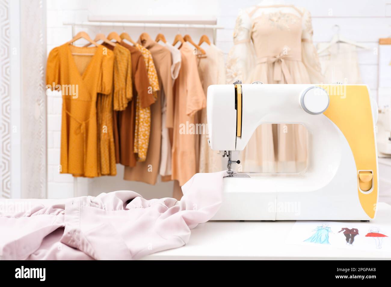 Modern sewing machine with fabric on table in dressmaking workshop ...
