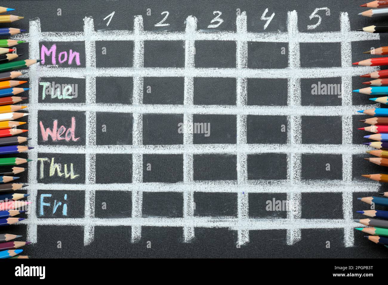 Colorful pencils and drawn weekly school timetable on black chalkboard ...