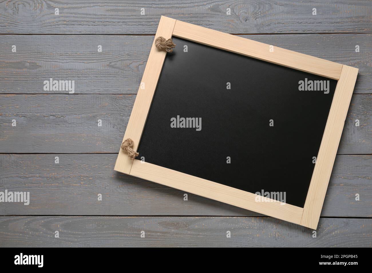 Clean small black chalkboard on grey wooden table, top view. Space for ...