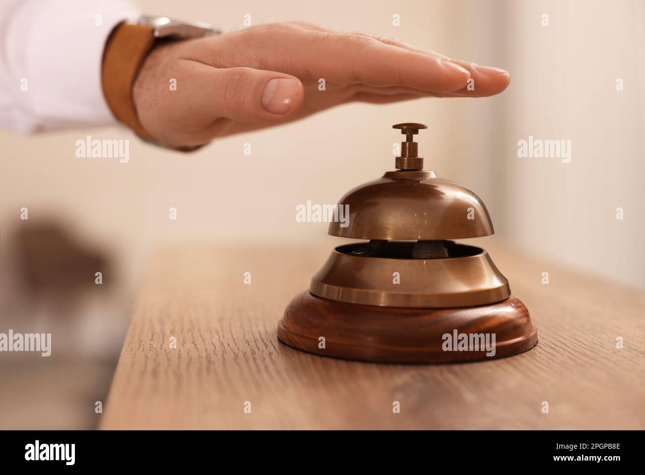 Man ringing service bell at wooden reception desk in hotel, closeup ...