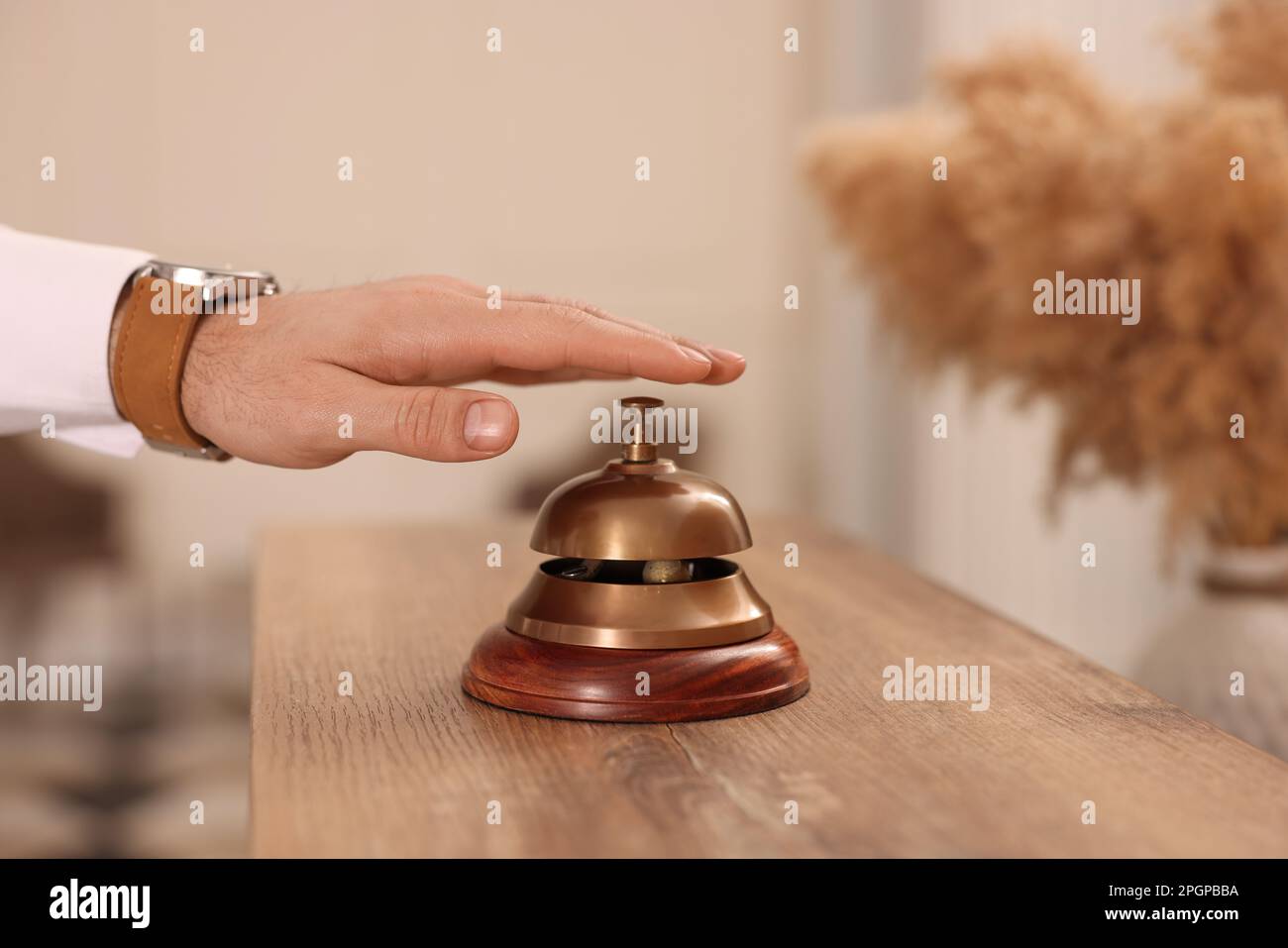 Man ringing service bell at wooden reception desk in hotel, closeup ...