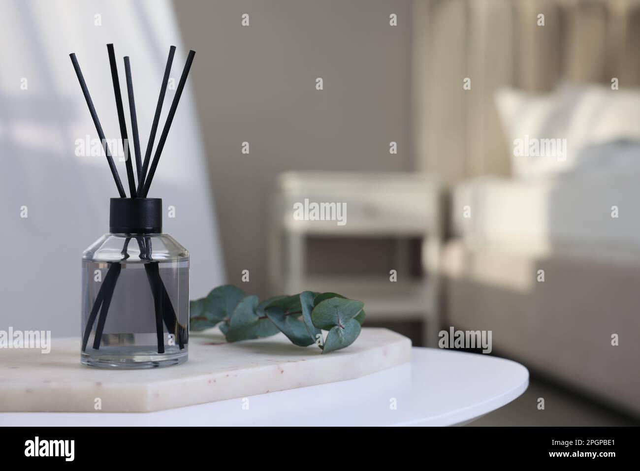 Aromatic reed air freshener and eucalyptus branch on white table in ...