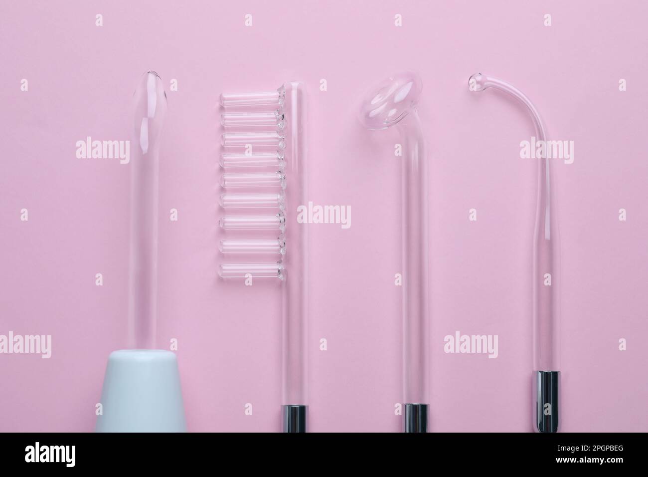 Modern darsonval with different nozzles on pink background, flat lay ...