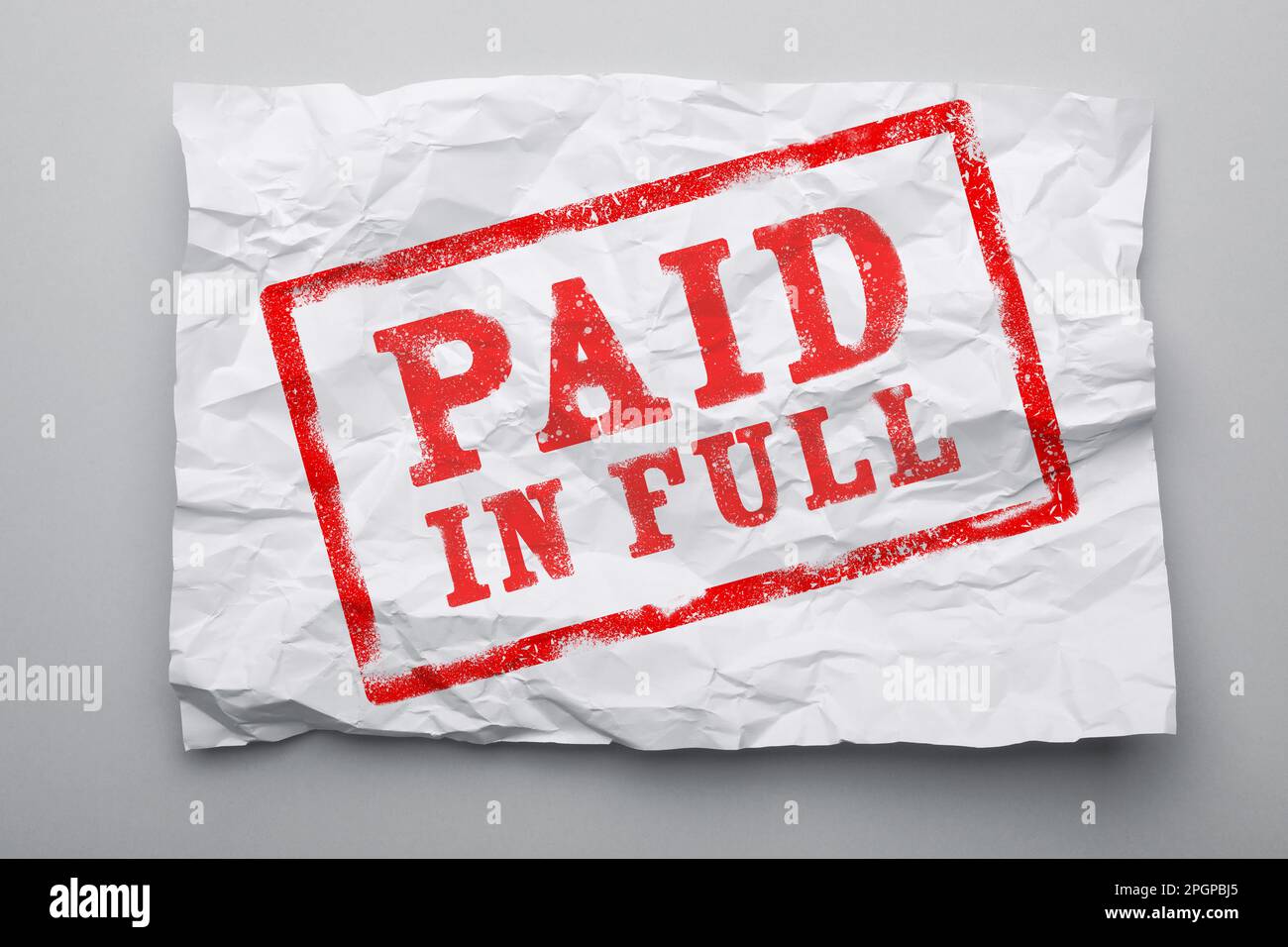 Crumpled paper with stamp PAID IN FULL on grey background, top view ...