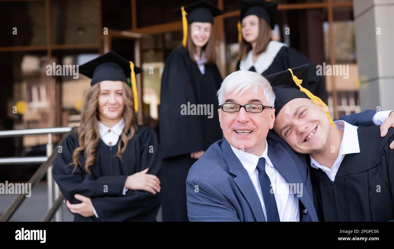 Father and son embrace at graduation. Parent congratulates university ...
