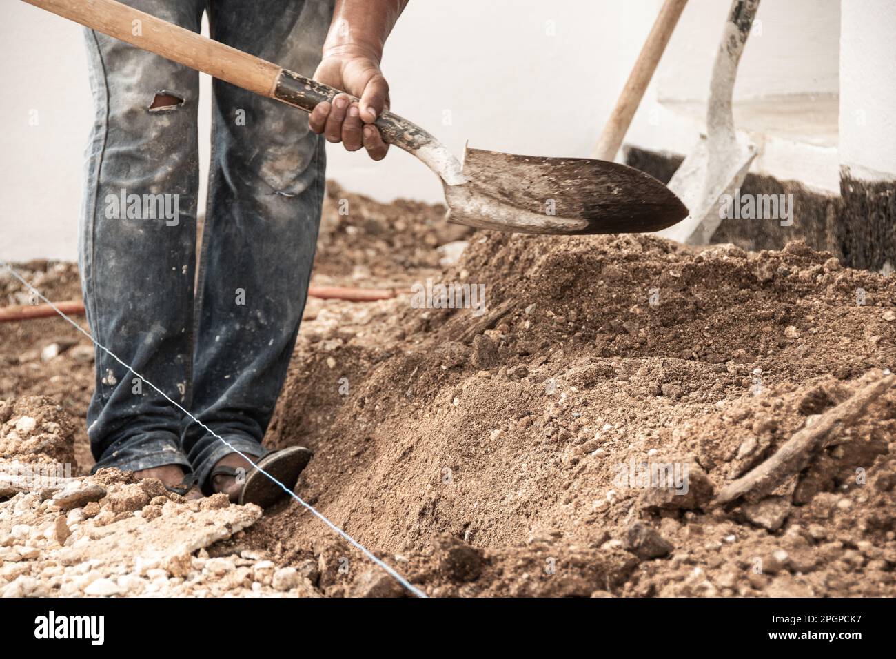 Man digging a hole in the ground with digging pick Stock Photo - Alamy