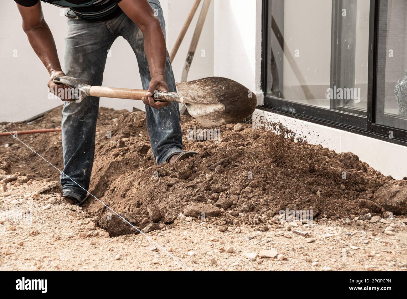 Man digging a hole in the ground with digging pick Stock Photo - Alamy