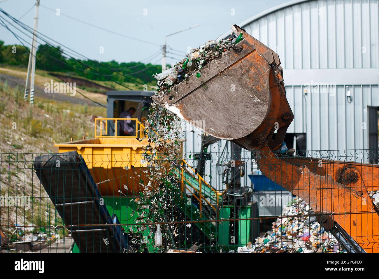 Pouring trash from excavator bucket on recycling plant yard Stock Photo ...