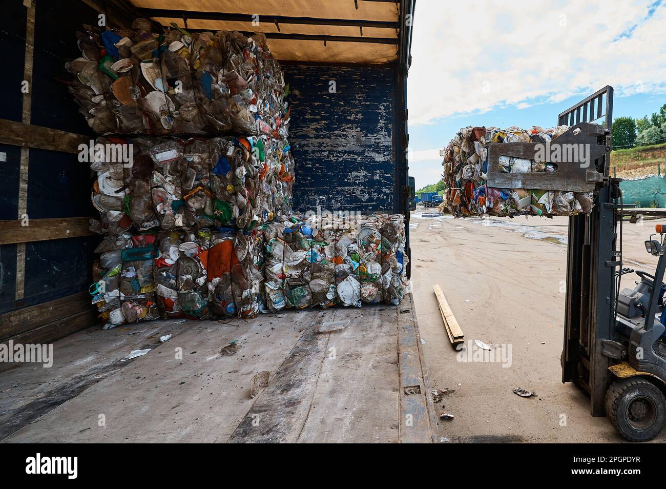 Forklift truck loads pressed plastic pack on shelf in yard Stock Photo ...