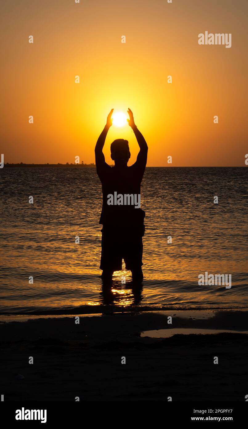 Silhouette of a man on the beach during sunset simulating catching the ...