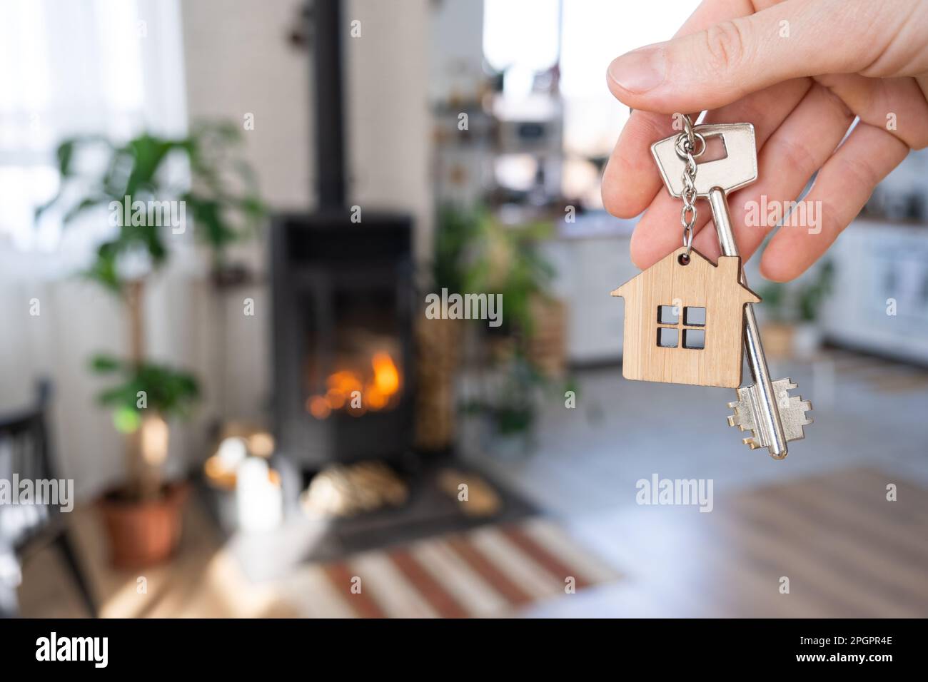 Key to house with keychain against background of fireplace stove with ...