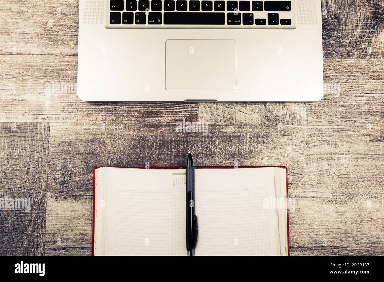 Open writing notebook next to a laptop from above view on a wooden ...