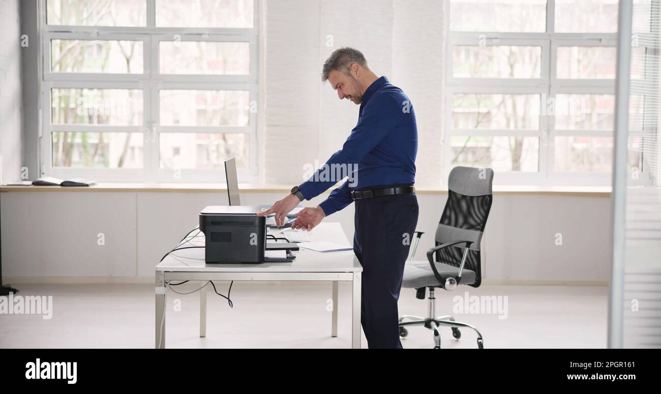 Irritated Businessman Looking At Paper Stuck In Printer At Office Stock ...