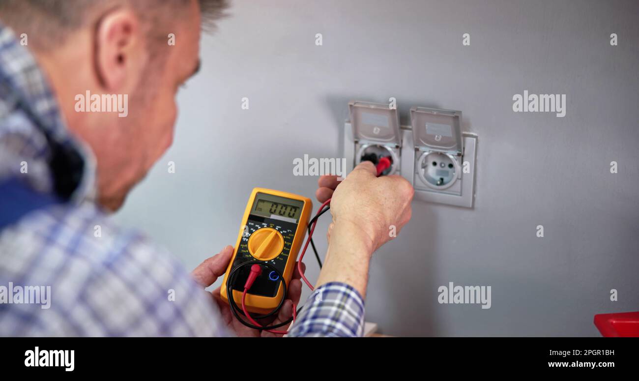 Male Electrician Checking Voltage Of Socket With Multimeter In House ...
