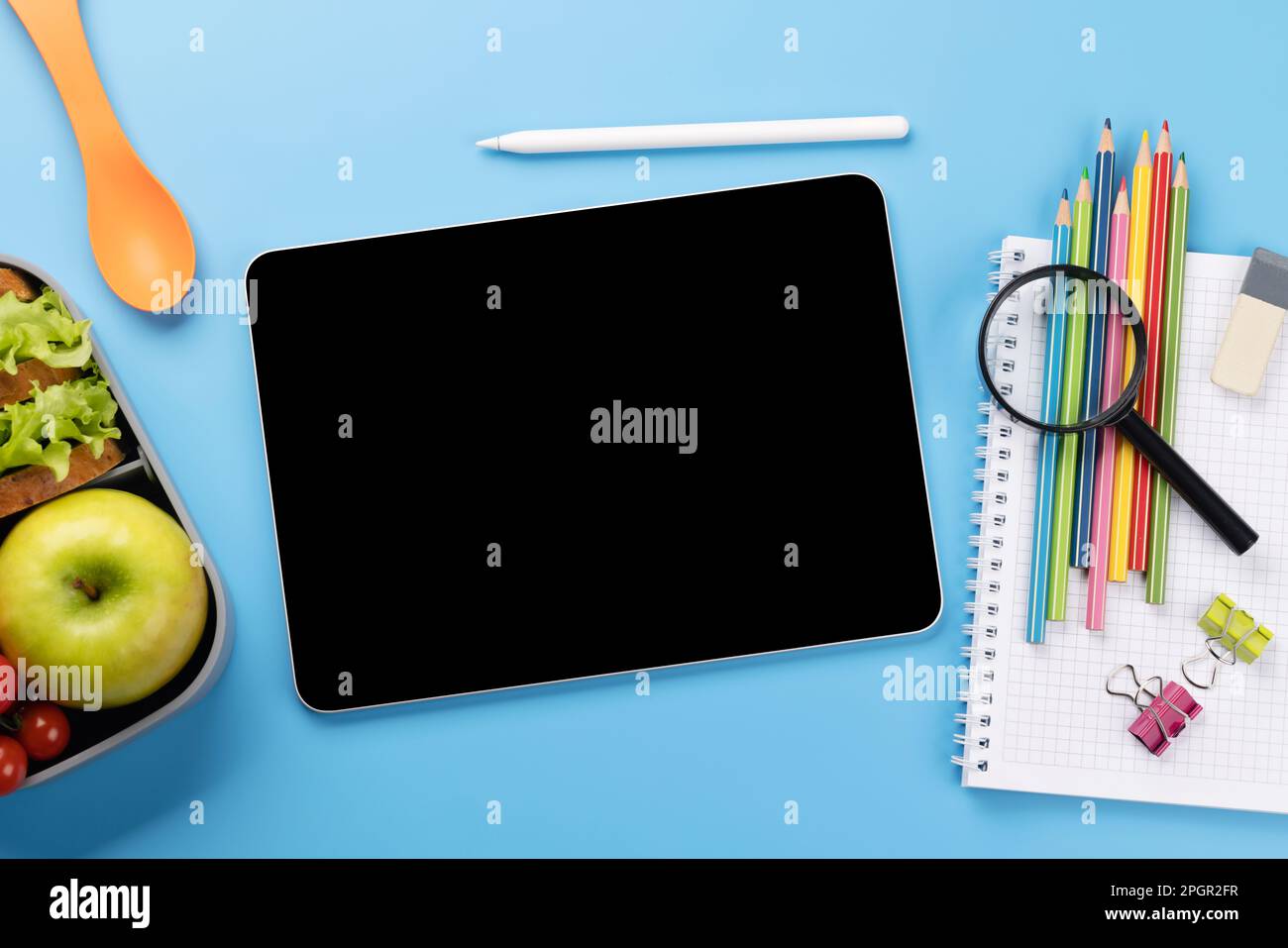 Tablet with blank screen, school supplies, stationery, and lunch box on ...