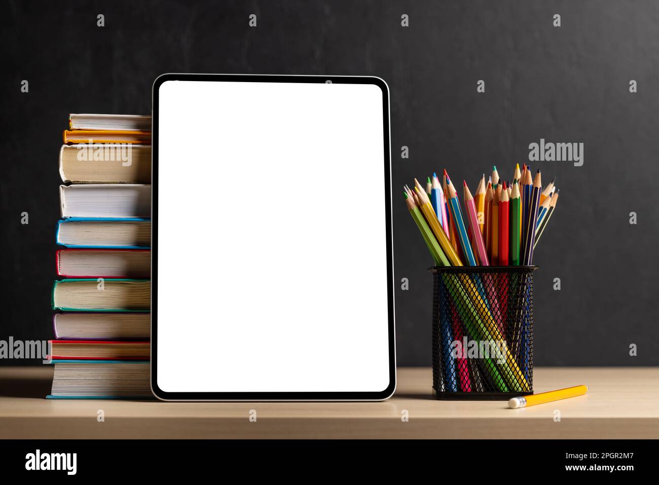 Tablet with colorful pencils and stack of books. With blank screen for ...