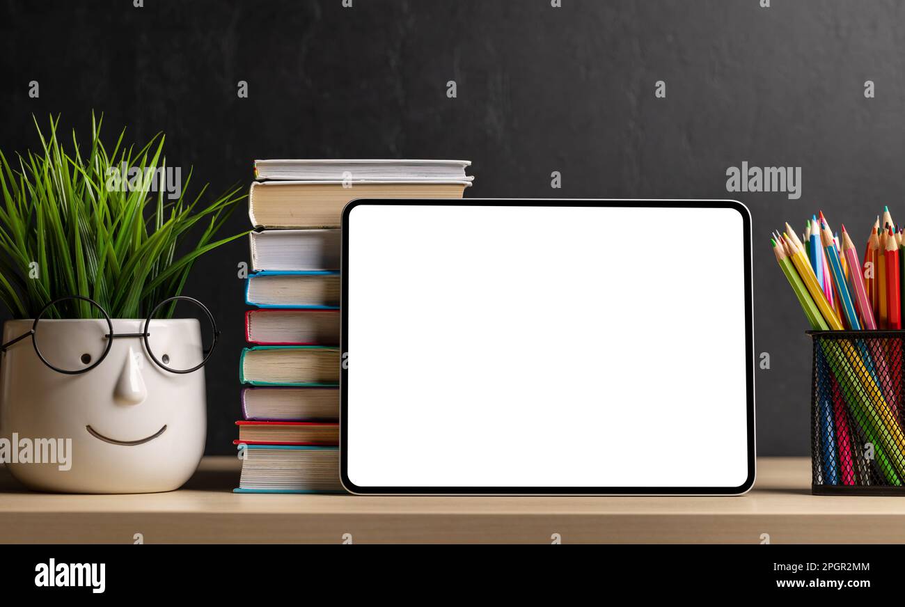 Tablet with colorful pencils and stack of books. With blank screen for ...