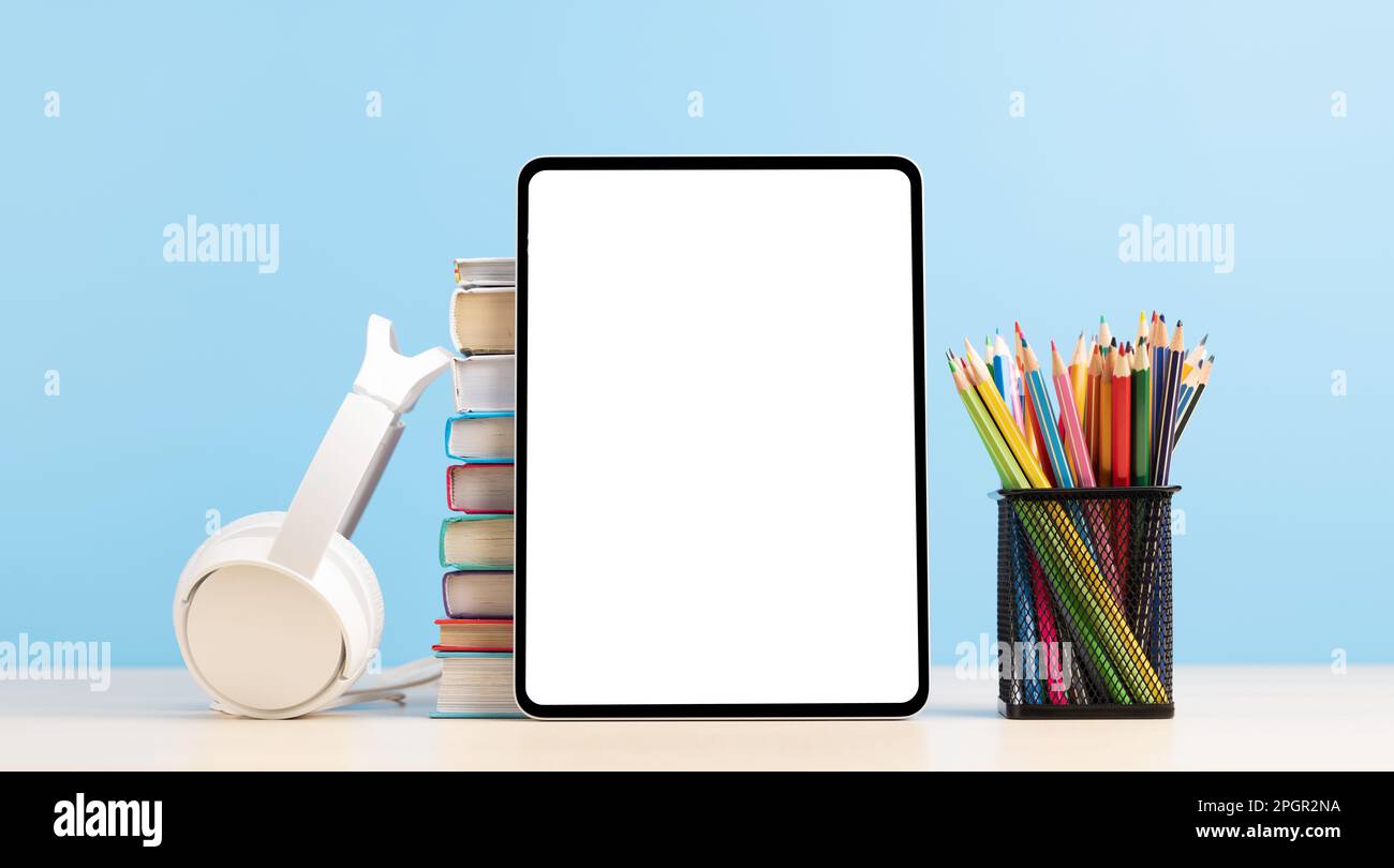 Tablet with colorful pencils and stack of books. With blank screen for ...