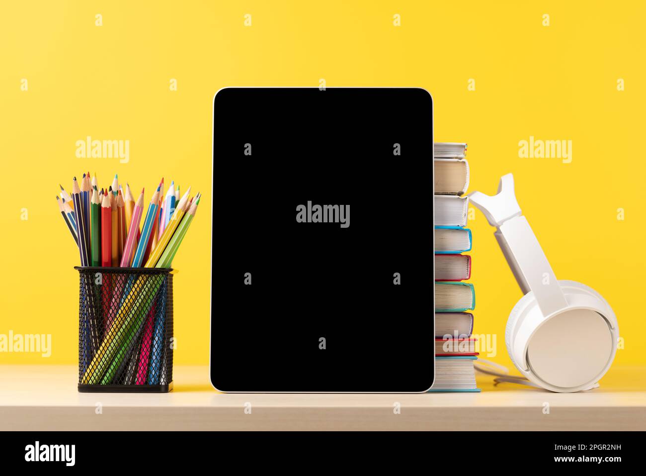 Tablet with colorful pencils and stack of books. With blank screen for ...
