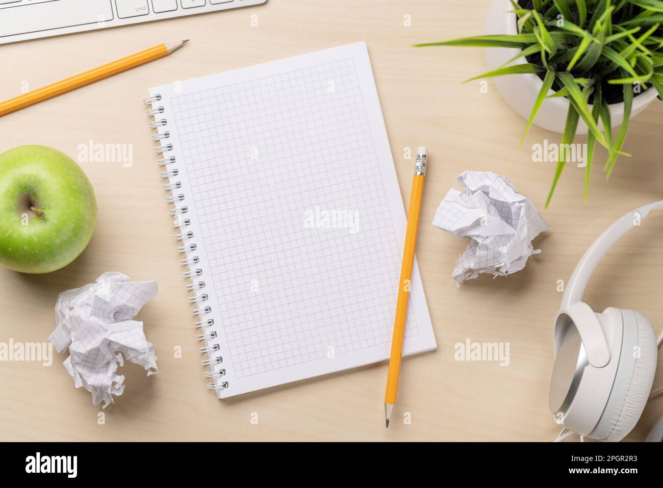 Top view of blank notepad, keyboard, headphones, apple and crumpled ...