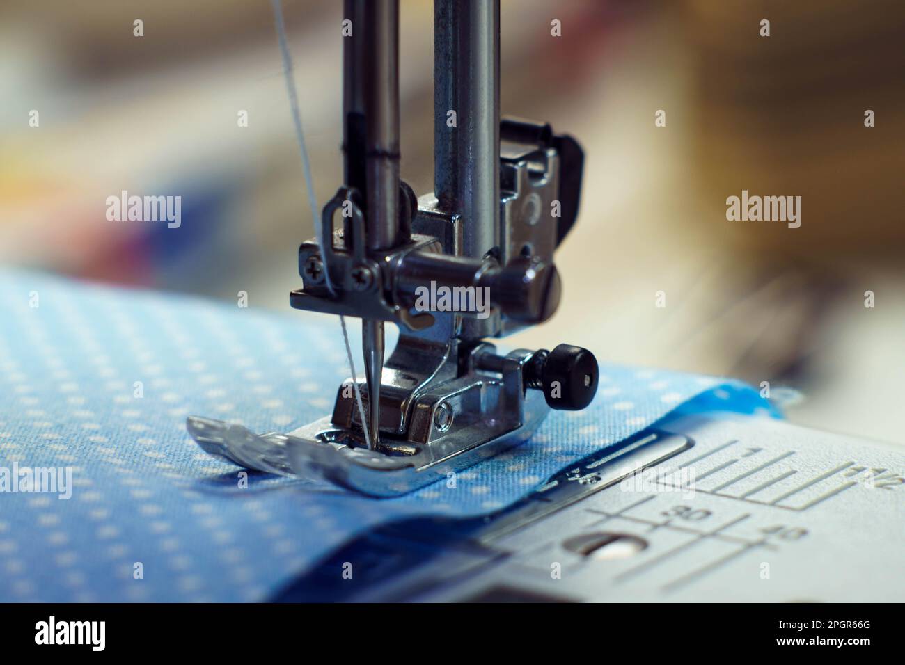 Macro shot of sewing machine steel pressure foot with needle and thread ...