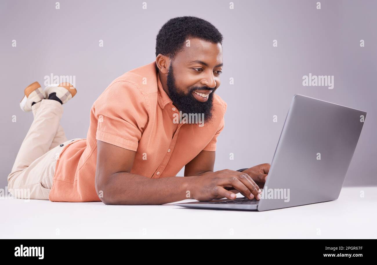 Happy black man, laptop and studio floor to search social media, online ...