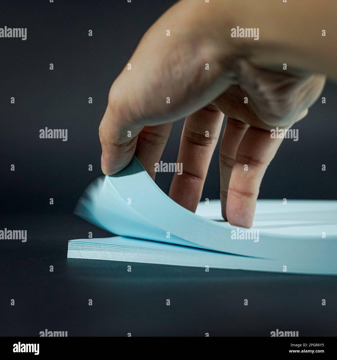 Stack of light blue colored paper with hand on frame Stock Photo - Alamy