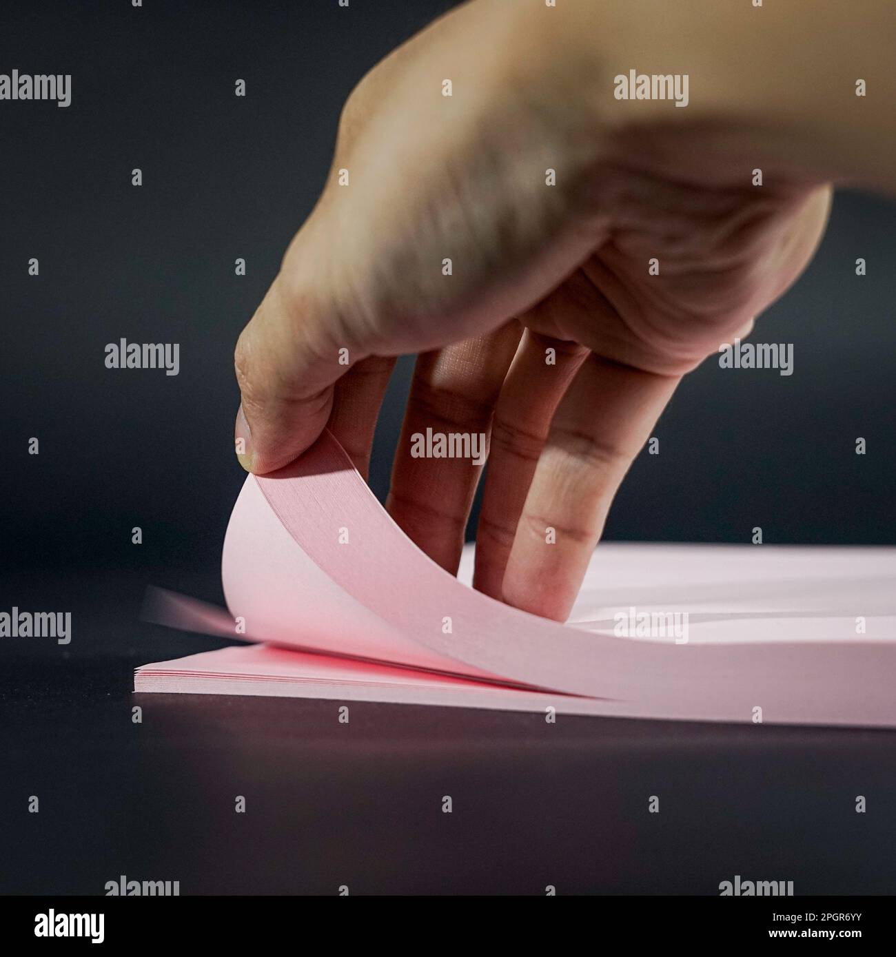 Stack of pink colored paper with hand on frame Stock Photo - Alamy