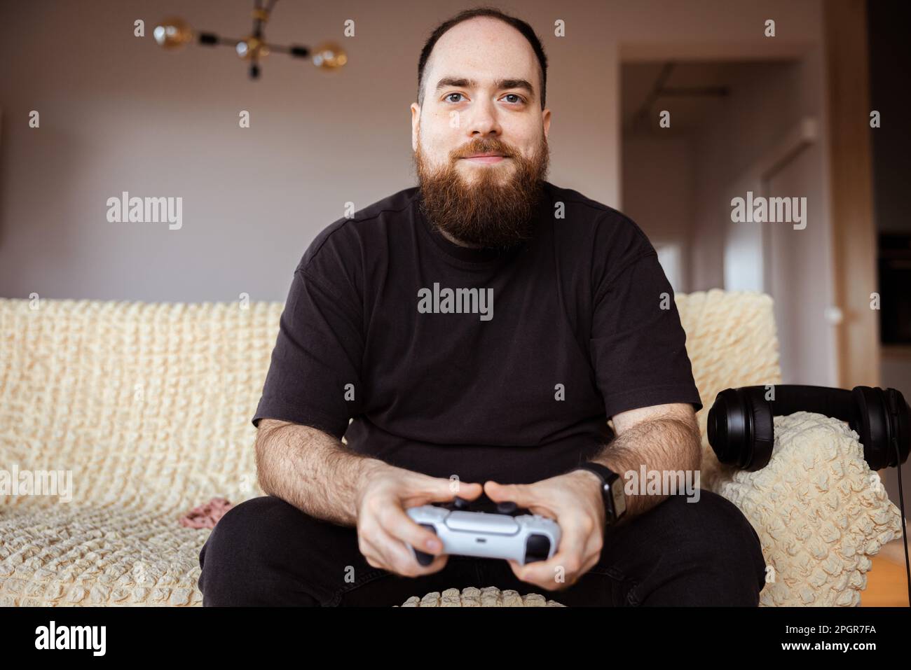 Focused male gamer dressed entirely in black clothing with a gaming ...