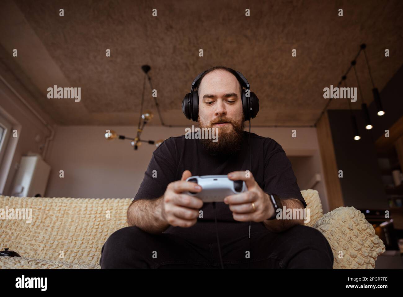 Lifestyle of a young male gamer playing on console with headsets on ...