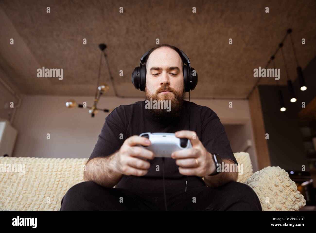 Lifestyle of a young male gamer playing on console with headsets on ...