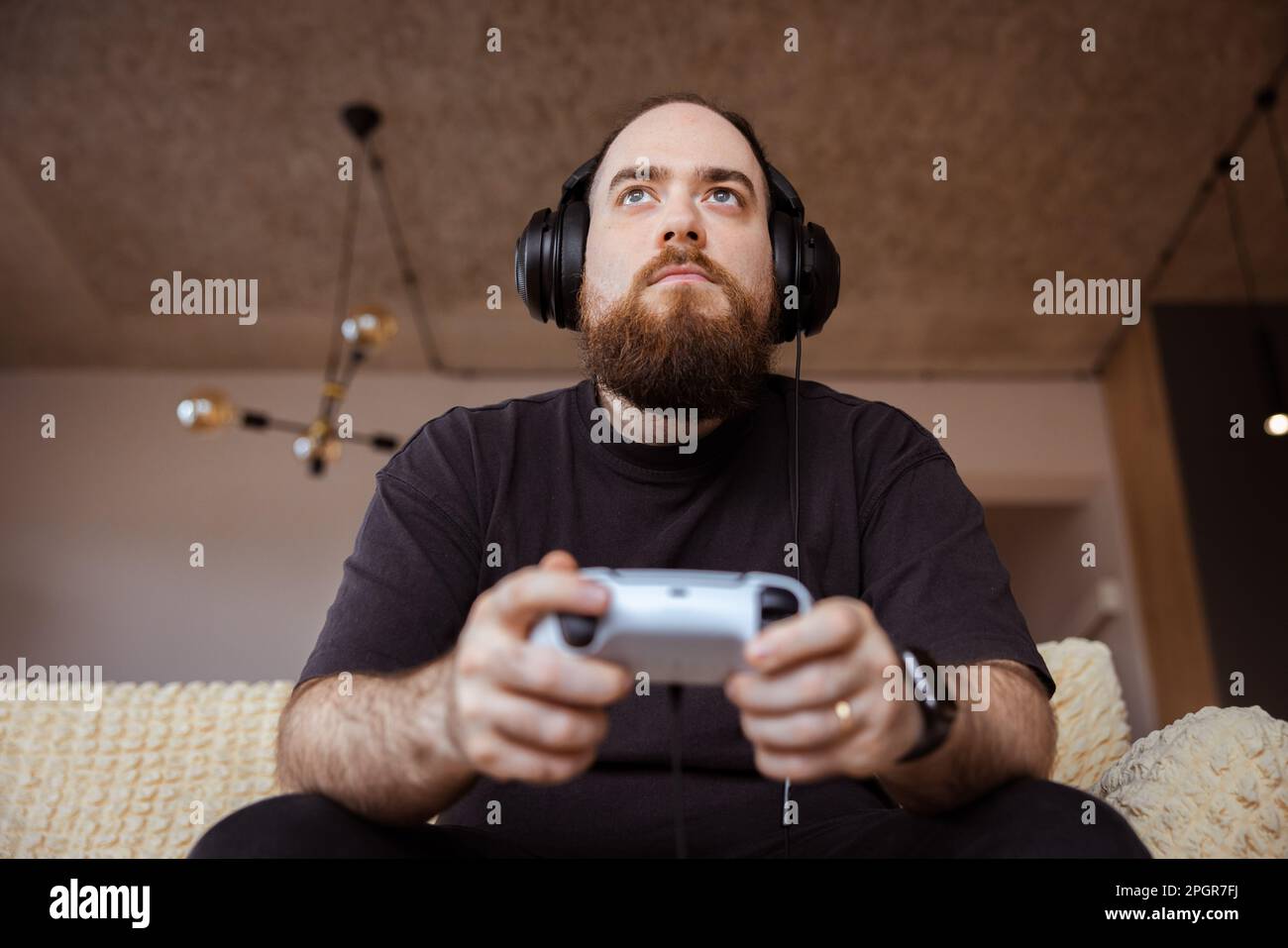 Lifestyle of a young male gamer playing on console with headsets on ...