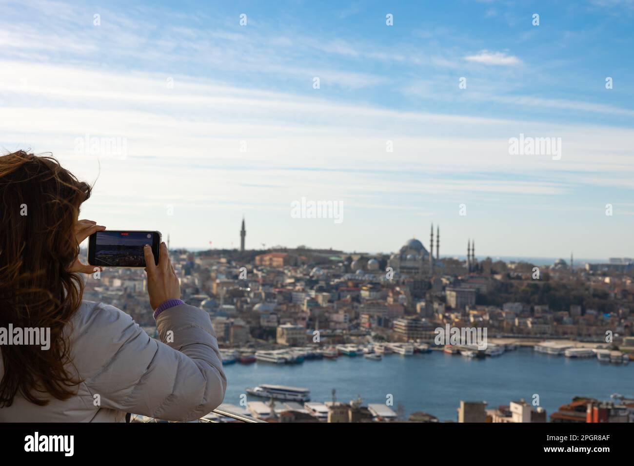 Woman taking photo of Istanbul with her mobile phone from Galata Tower ...