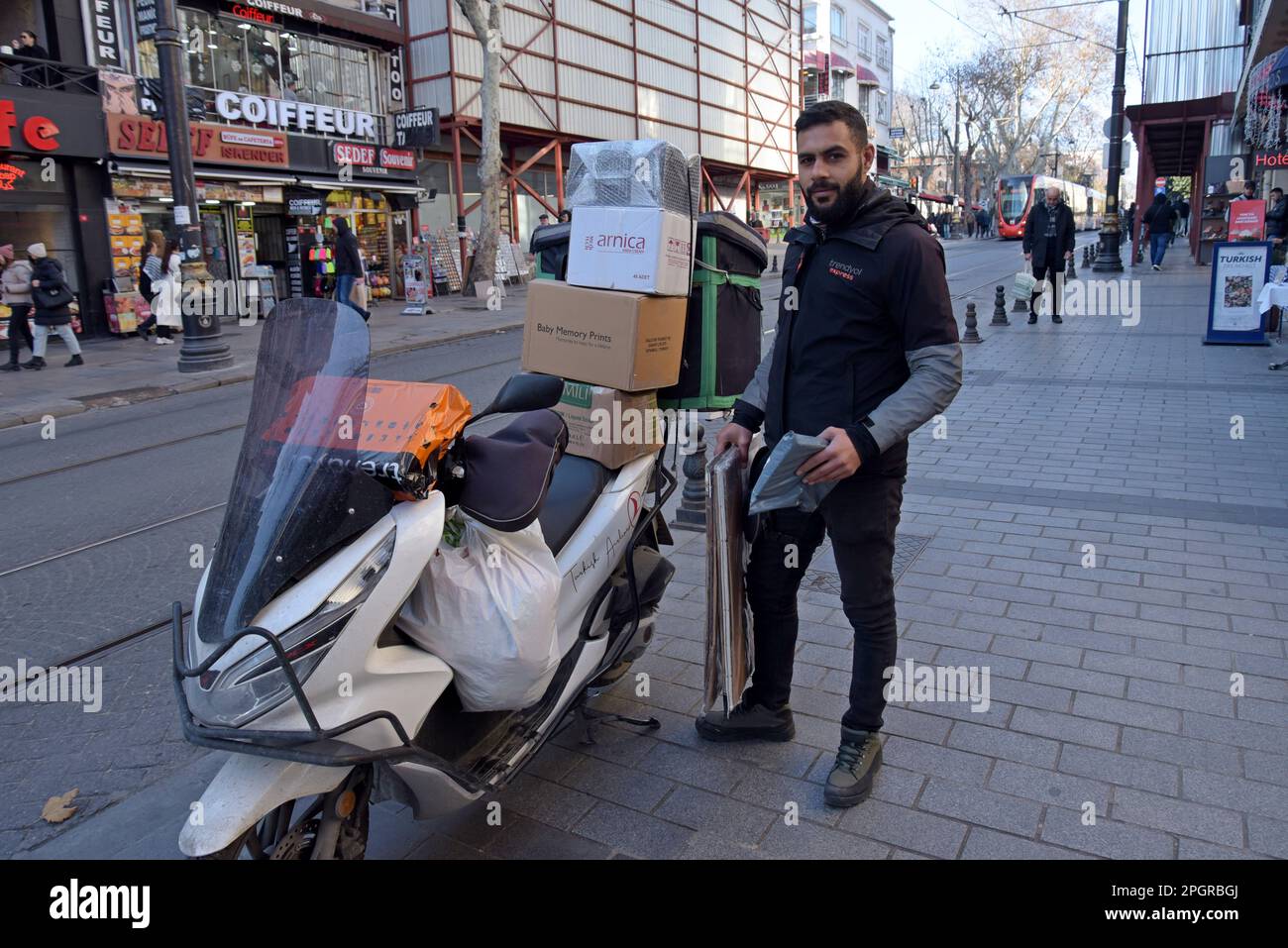 A parcel delivery courier showing his moped stacked high with packages ...