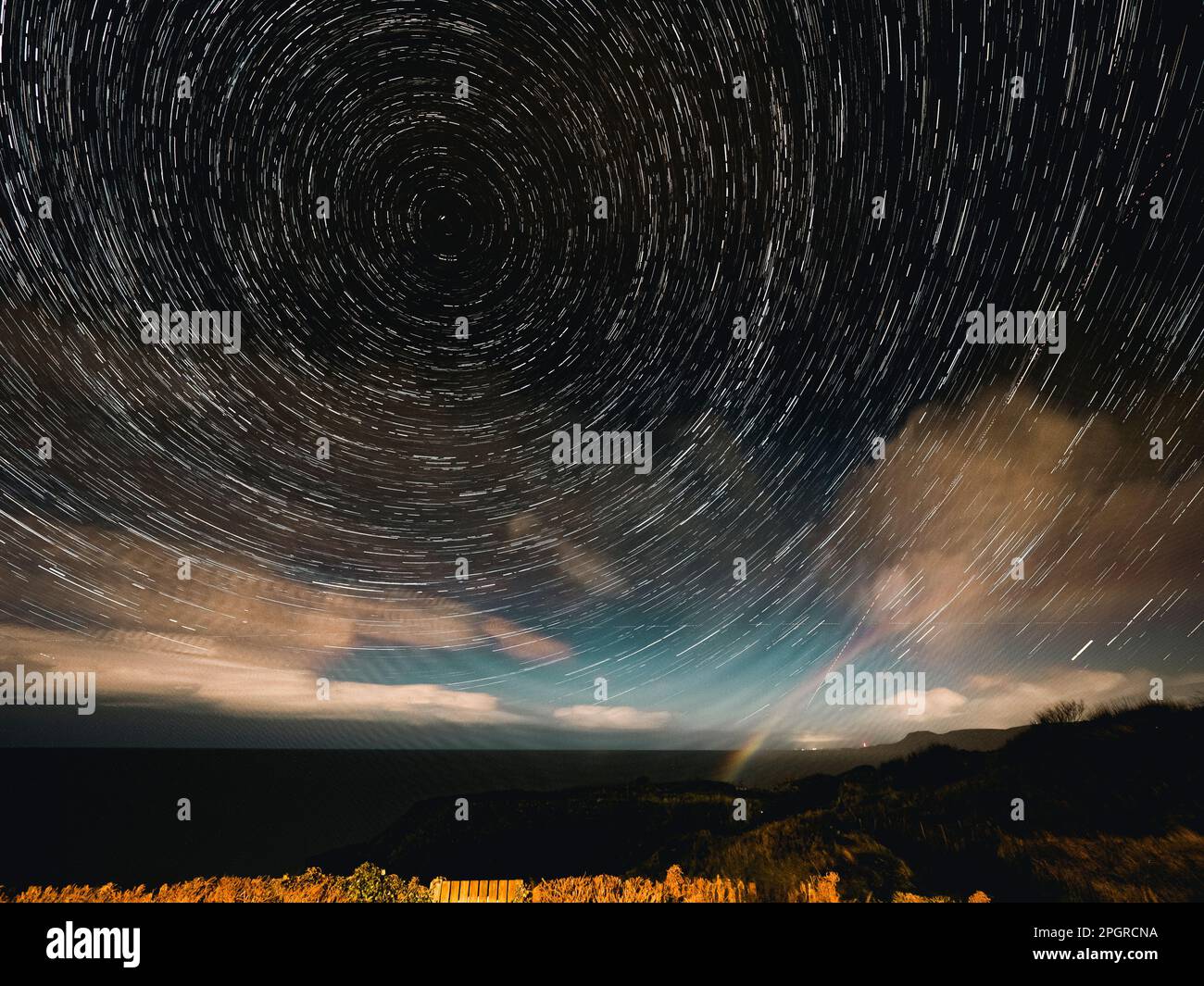 Start trails and rainbows over a coastline. Stars rotate and rain ...