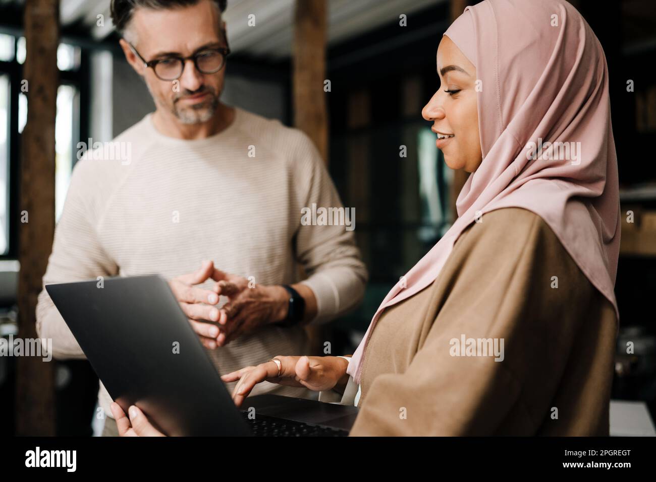 Two multinational colleagues working with laptop computer in modern ...