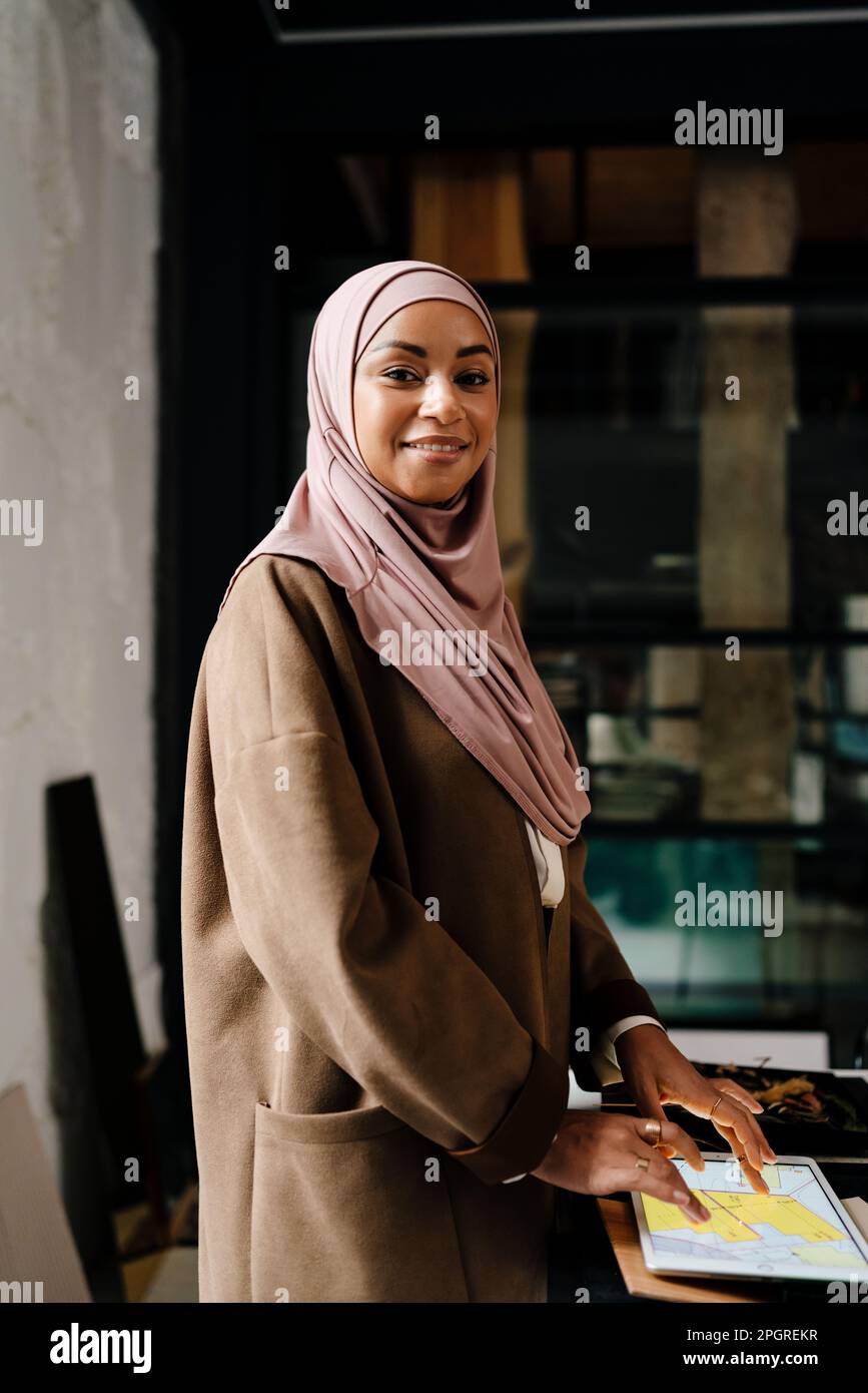 Female muslim designer wearing hijab working on tablet at workshop ...