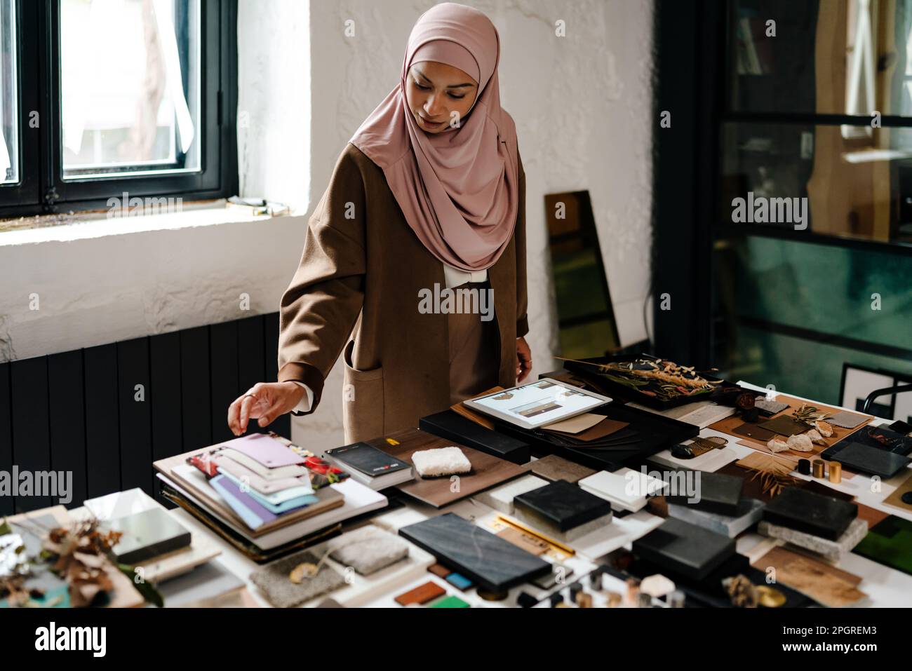 Female muslim architect wearing hijab working on tablet at workshop ...