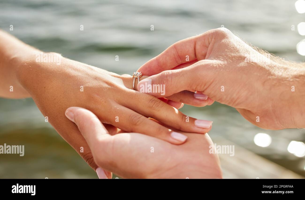 Hands, proposal and engagement ring at lake outdoors for couple ...