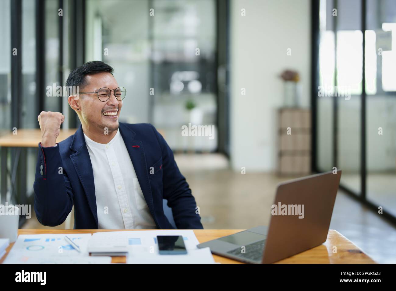 Portrait of an Asian male business owner standing with a computer ...