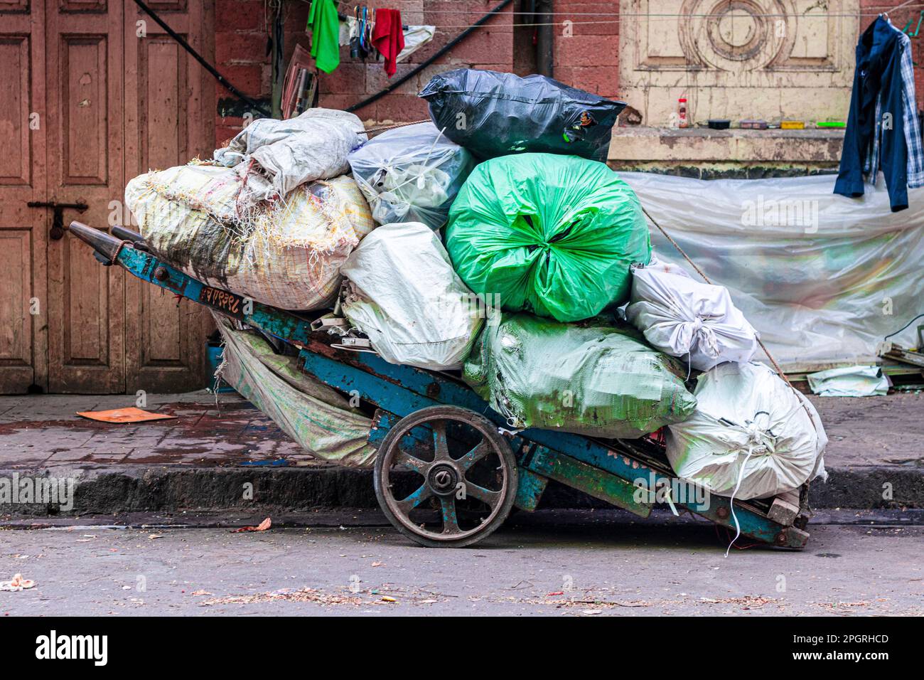 A wheelbarrow full of garbage on the side of a street Stock Photo - Alamy