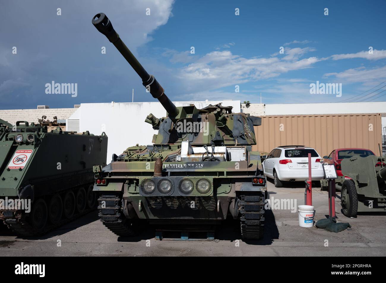 Two military vehicles parked side-by-side in front of a large structure ...