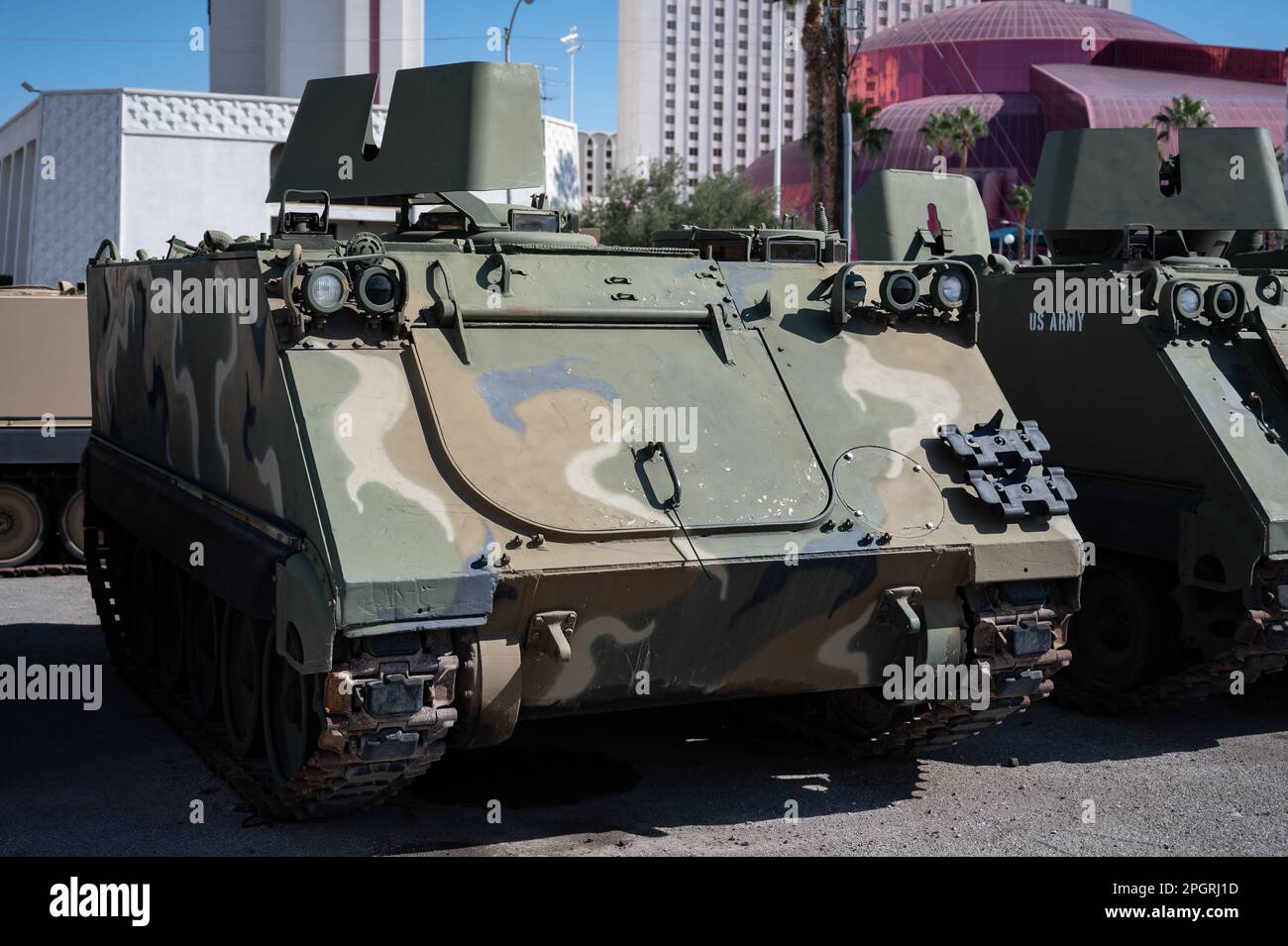 A fleet of military tanks are parked in a row in front of a cityscape ...