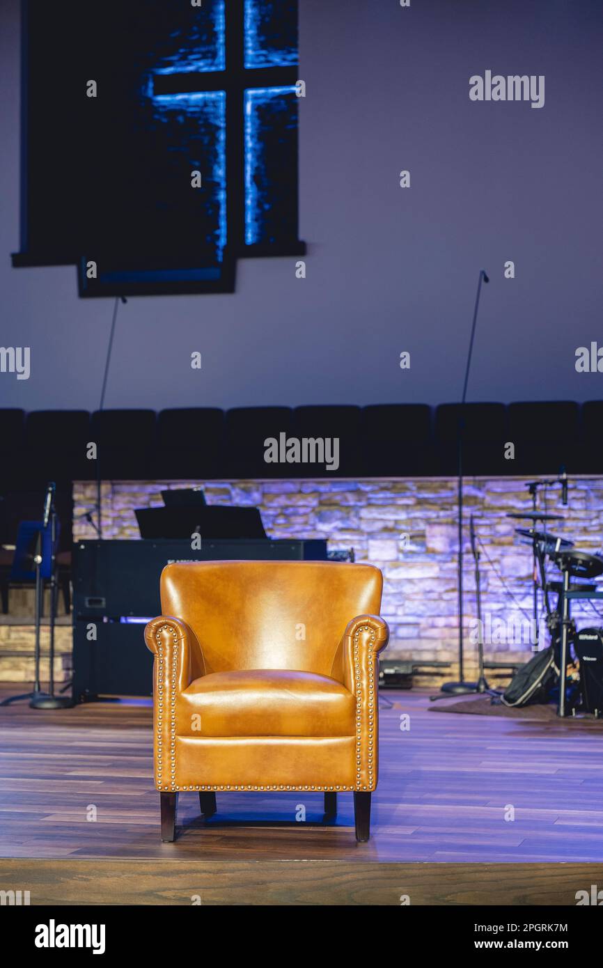 A brown leather armchair on the stage with musical instruments and a ...