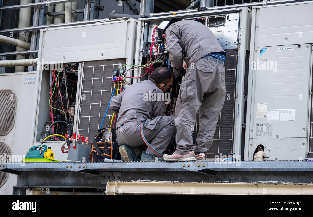 March 13th 2023 - Tokyo, Japan: Japanese engineers fixing an air conditioning unit with wires ...