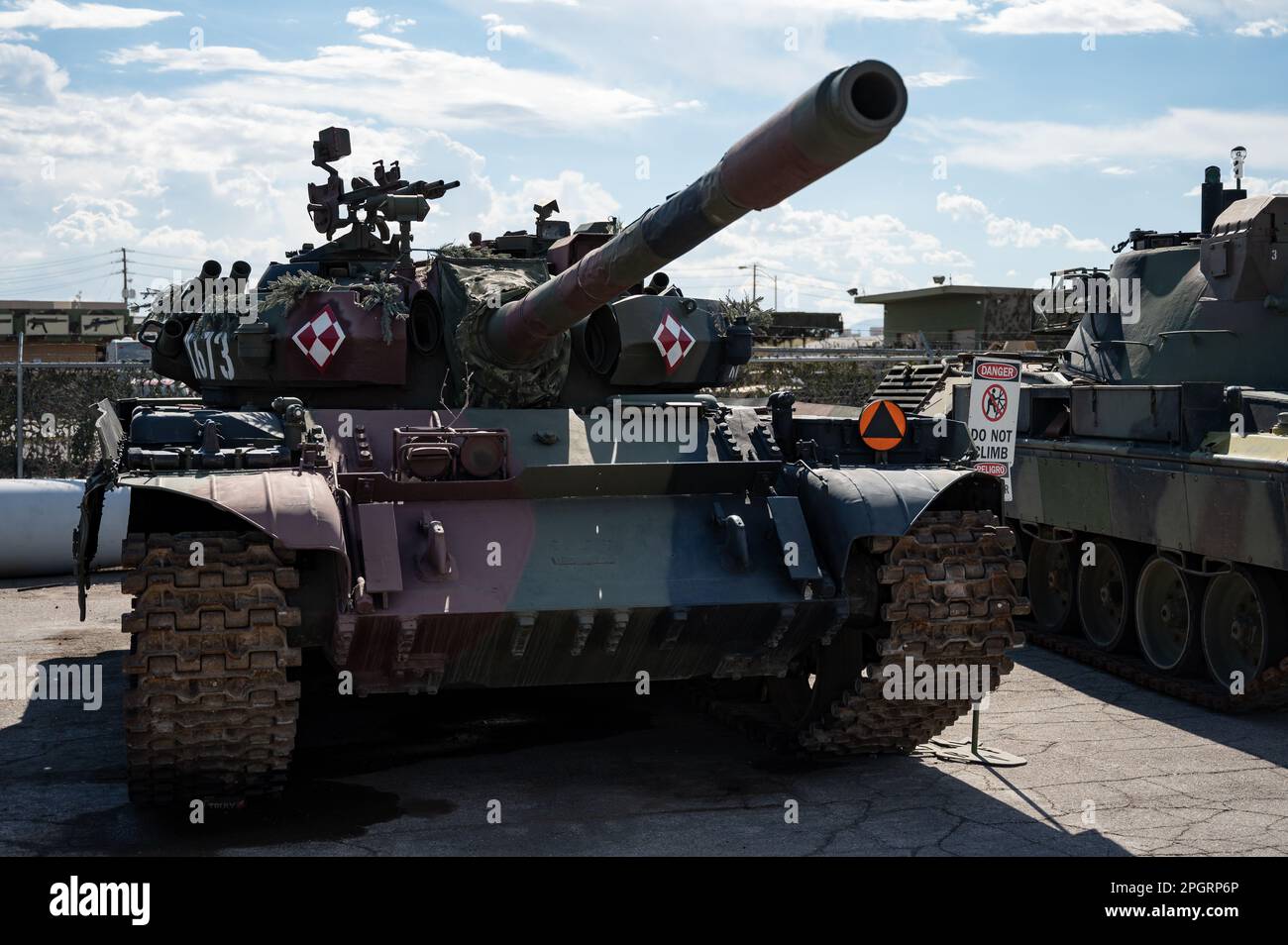 A group of military tanks are parked in a straight line on the pavement ...