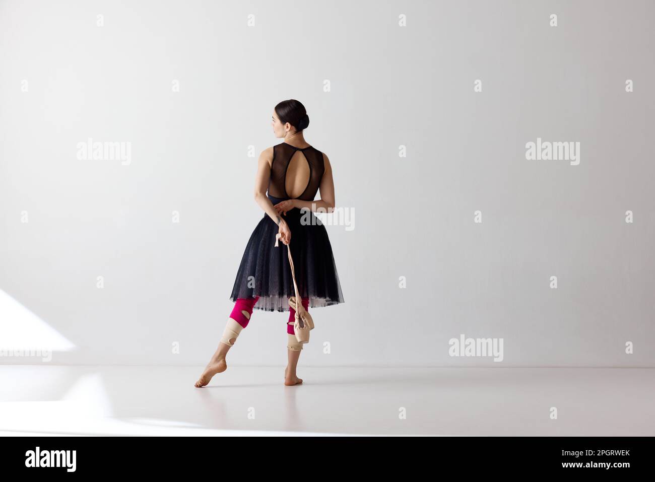 Back view. Young and graceful ballet dancer wearing black dress posing ...